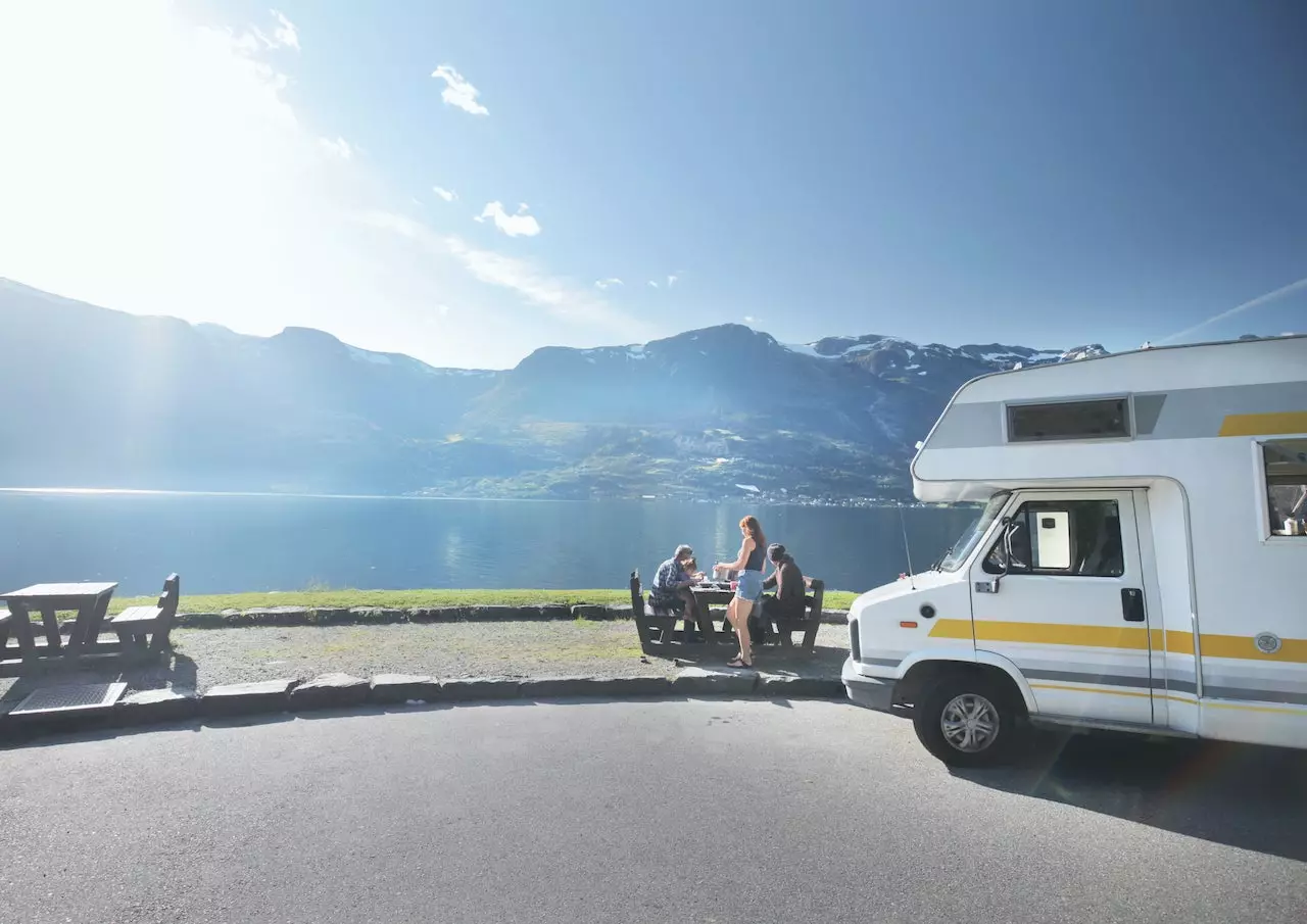 Familia almorzando en autocaravana cerca del lago y las montañas