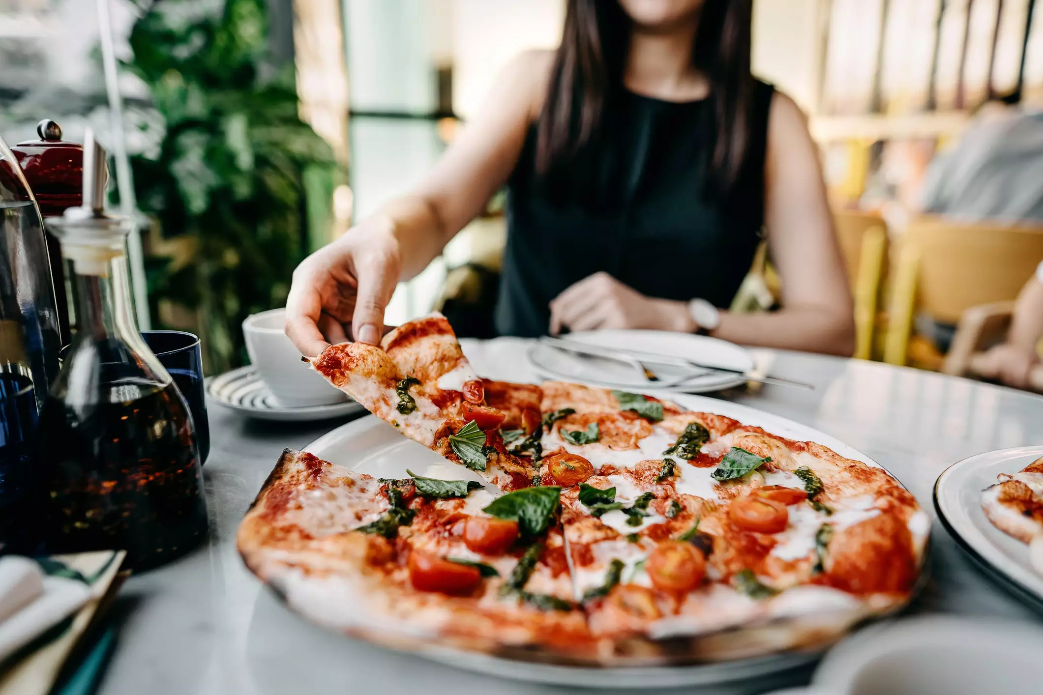 Deukeut awéwé ngora Asia ngarasakeun pizza anyar dijieun di réstoran Italia