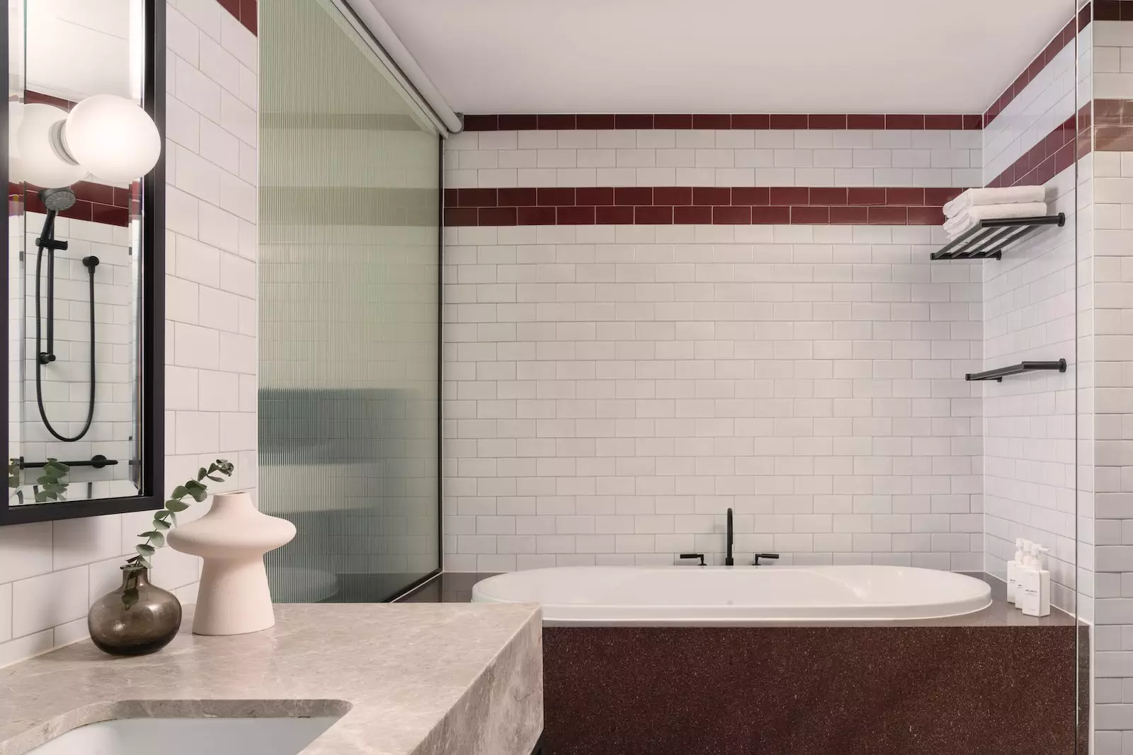 banyo ng hotel na may malaking bathtub, puting subway tile at lababo