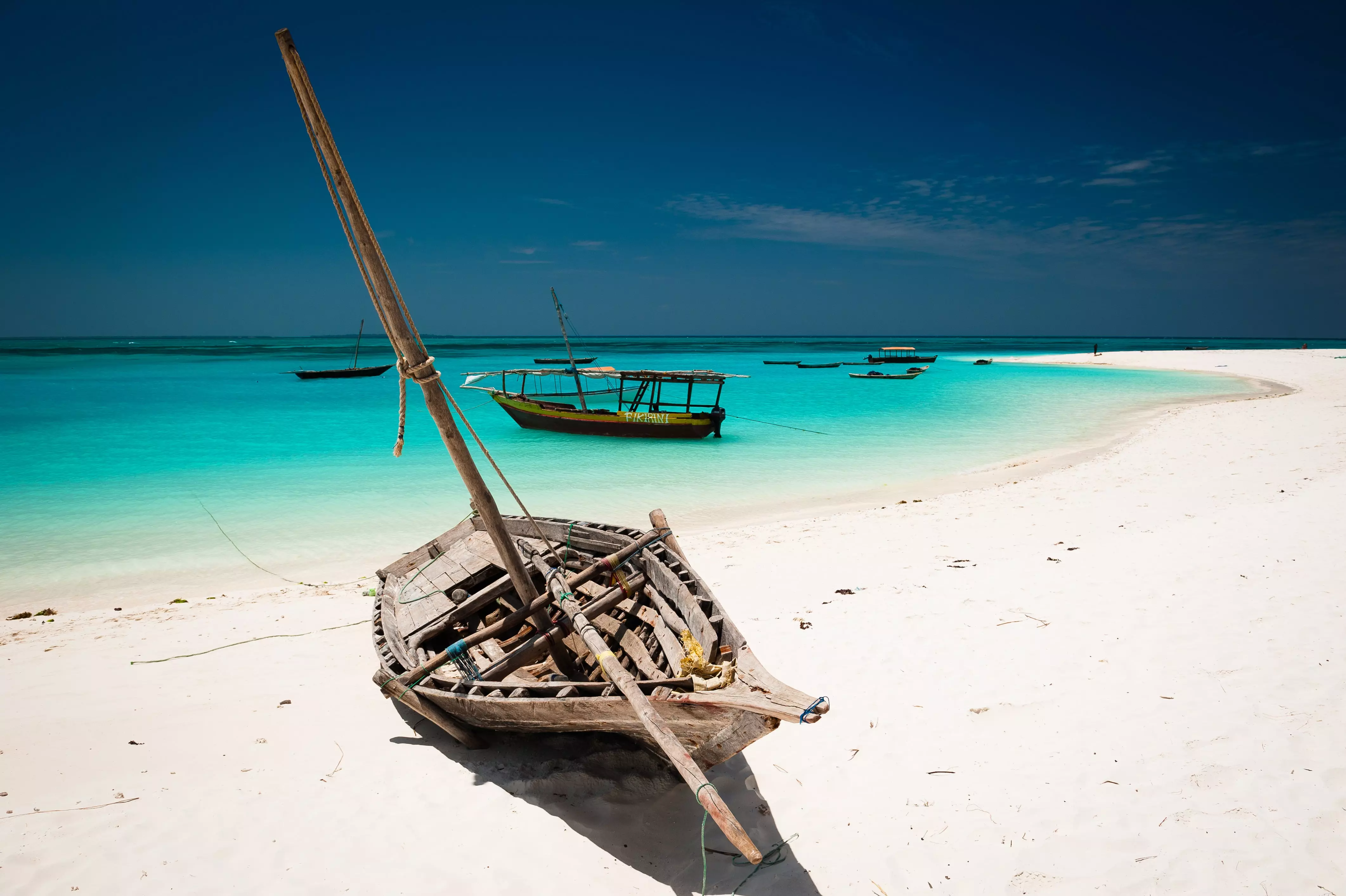 Stará dhow leží na pláži Kendwa s tyrkysovými vodami Indického oceánu v pozadí, Zanzibar, Tanzánia