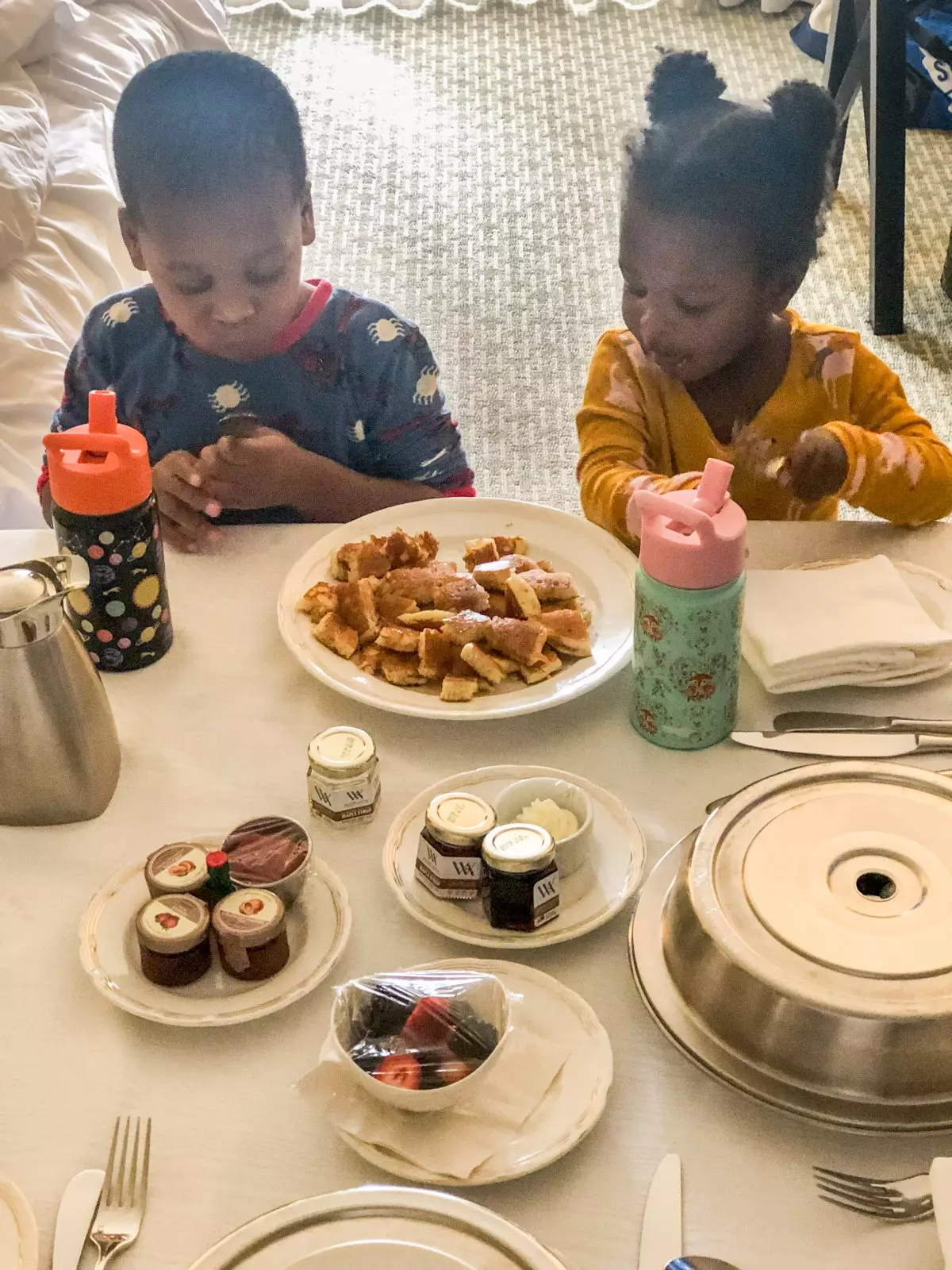 Dos niños disfrutando de los panqueques del servicio de habitaciones.