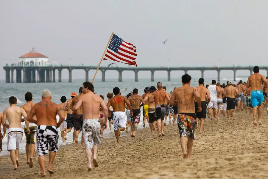 Deelnemers rennen het strand af richting de Manhattan Beach-pier tijdens de eerste etappe van de Iron Man op 4 juli.