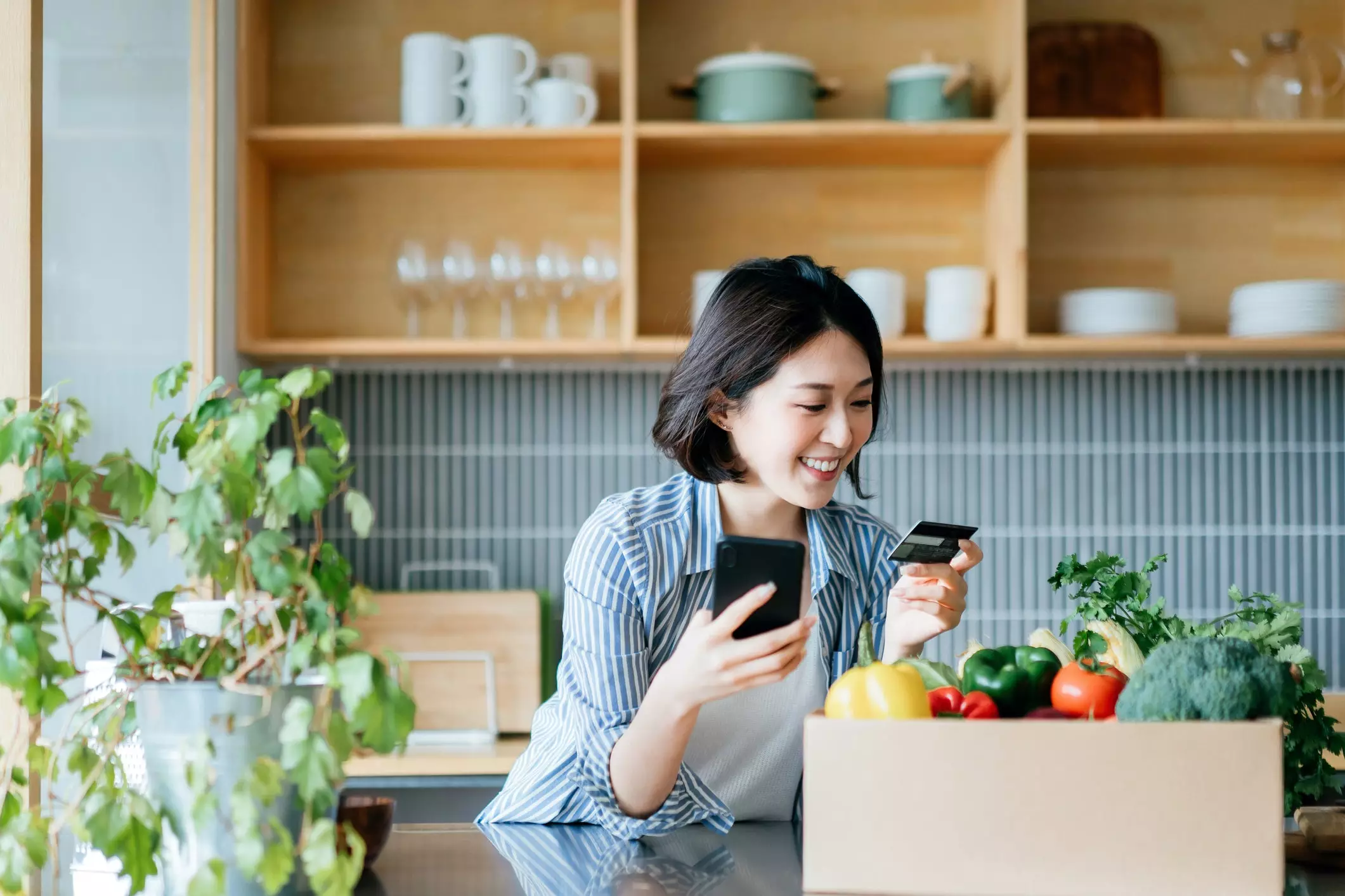 Mujer usando teléfono celular y con tarjeta de crédito