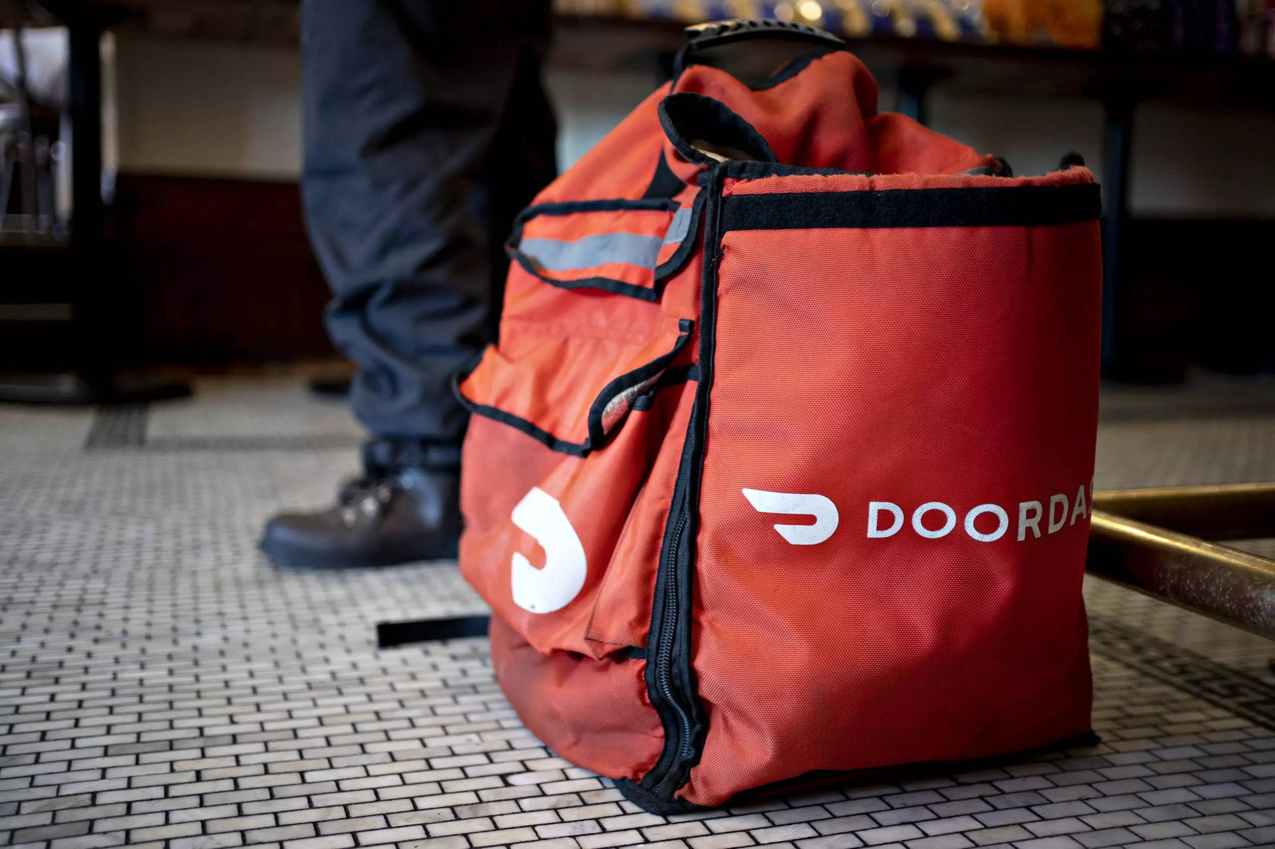 Taška DoorDash Inc. leží na podlaze v restauraci šéfkuchaře Geoffa ve Washingtonu, D.C., USA, ve čtvrtek 26. března 2020. Kola vlády se otáčejí příliš pomalu a malé podniky zoufale hledají část úlevy ve výši 2 bilionů dolarů balíček kvůli pandemii koronaviru, restauratér Geoff Tracy používá GoFundMe, aby získal peníze pro 150 hodinových pracovníků ve své americké pohotovostní restauraci Chef Geoff's a dalších restauracích. Fotograf: Andrew Harrer/Bloomberg prostřednictvím Getty Images