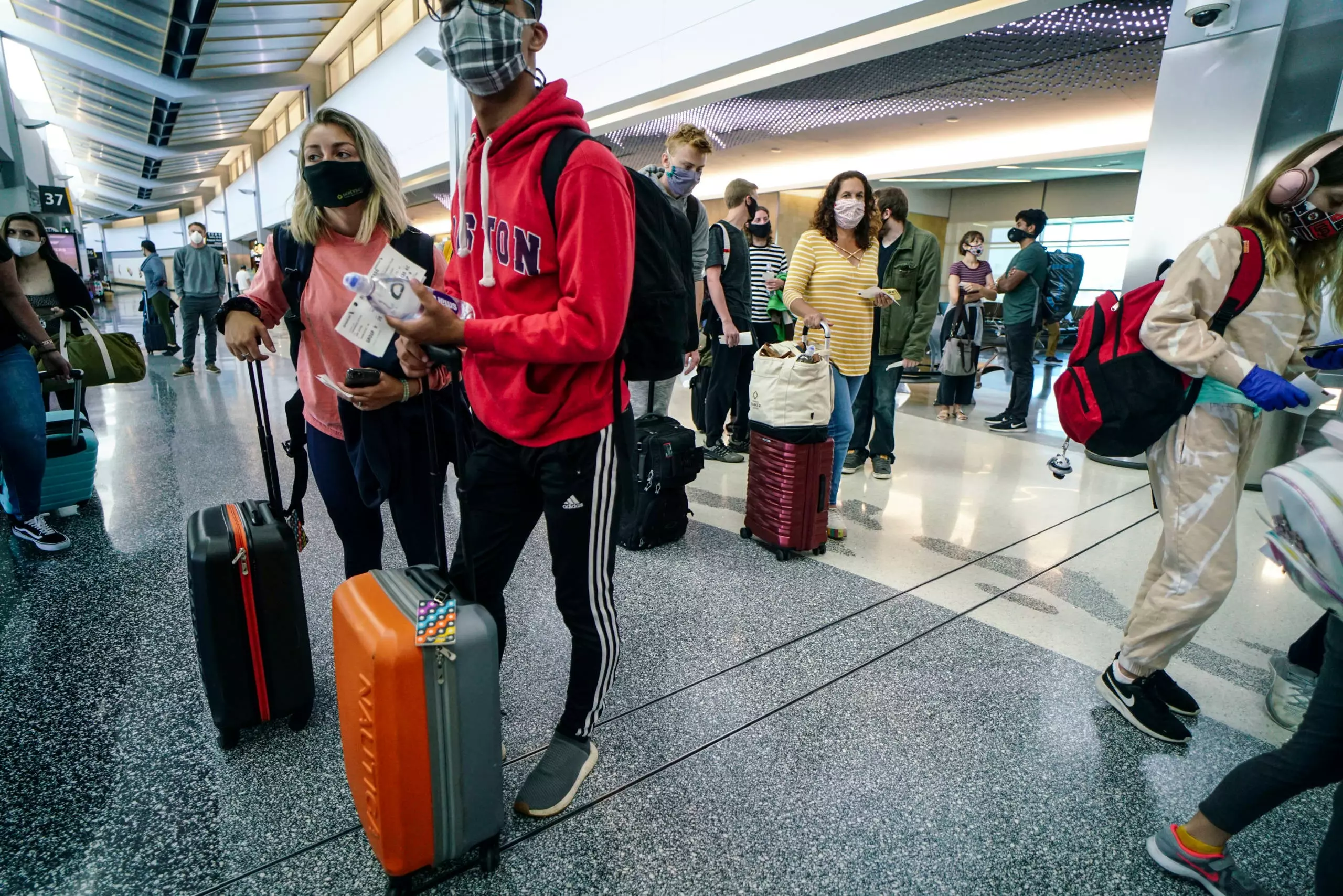 SAN DIEGAS, CA–GEGUŽĖS 20 d.: 2020 m. gegužės 20 d. San Diege, Kalifornijoje, keleiviai įlipa į „American Airlines“ skrydį į Šarlotę, Šiaurės Karoliną, San Diego tarptautiniame oro uoste. Apskaičiuota, kad dėl koronaviruso (COVID-19) pandemijos kelionių lėktuvu sumažėjo 94 proc., todėl JAV oro linijos patiria didelį finansinį smūgį – nuostoliai siekia 350–400 mln. USD per dieną, nes beveik pusė pagrindinių vežėjų lėktuvų neveikia. (Nuotrauka Sandy Huffaker / Getty Images)