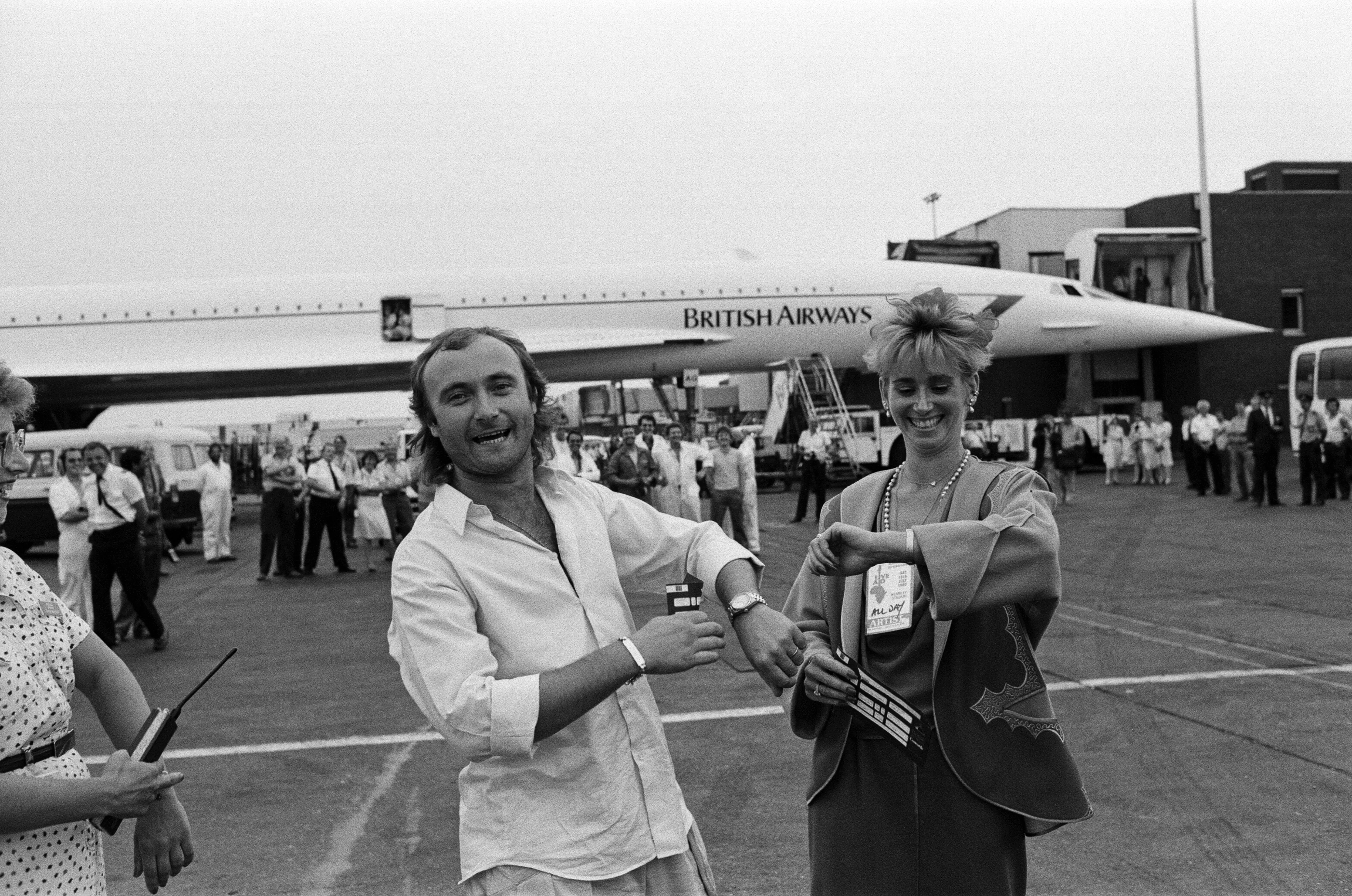 Sångaren Phil Collins och fru Jill Travelman på London Heathrow Airport. Phil Collins är på väg att gå ombord på ett Concorde-flyg till USA, för att uppträda på JFK Stadium i Philadelphia, i Live Aid-konserten. Phil har redan uppträtt på motsvarande Live Aid-show på Wembley Stadium, 13 juli 1985. (Foto Dennis/Mirrorpix/Getty Images)