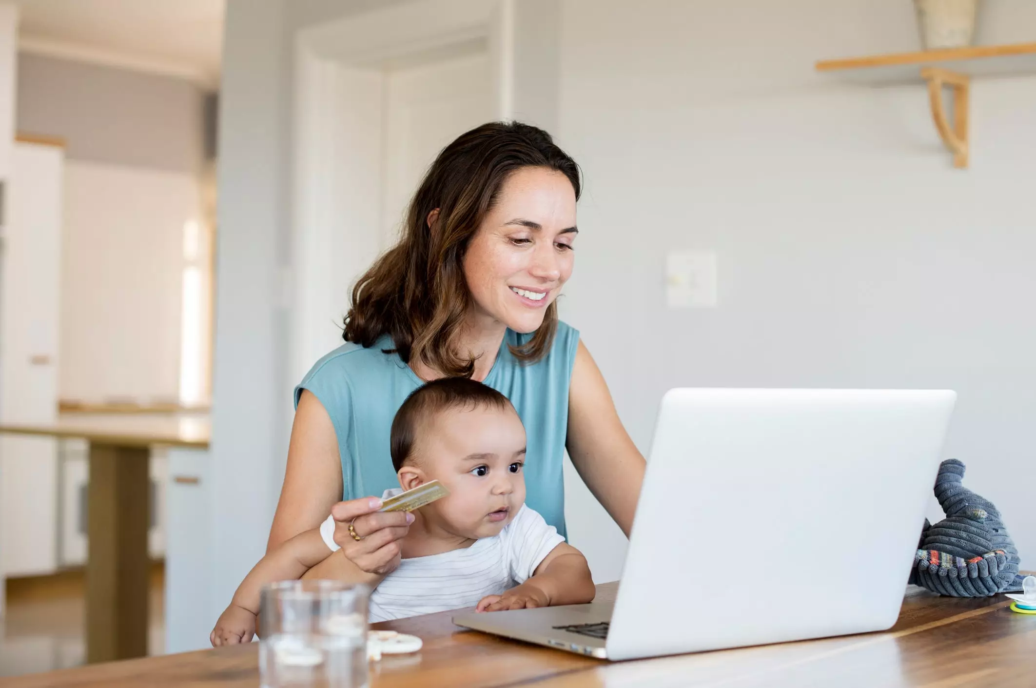 femeie și bebeluș cu laptop și card de credit