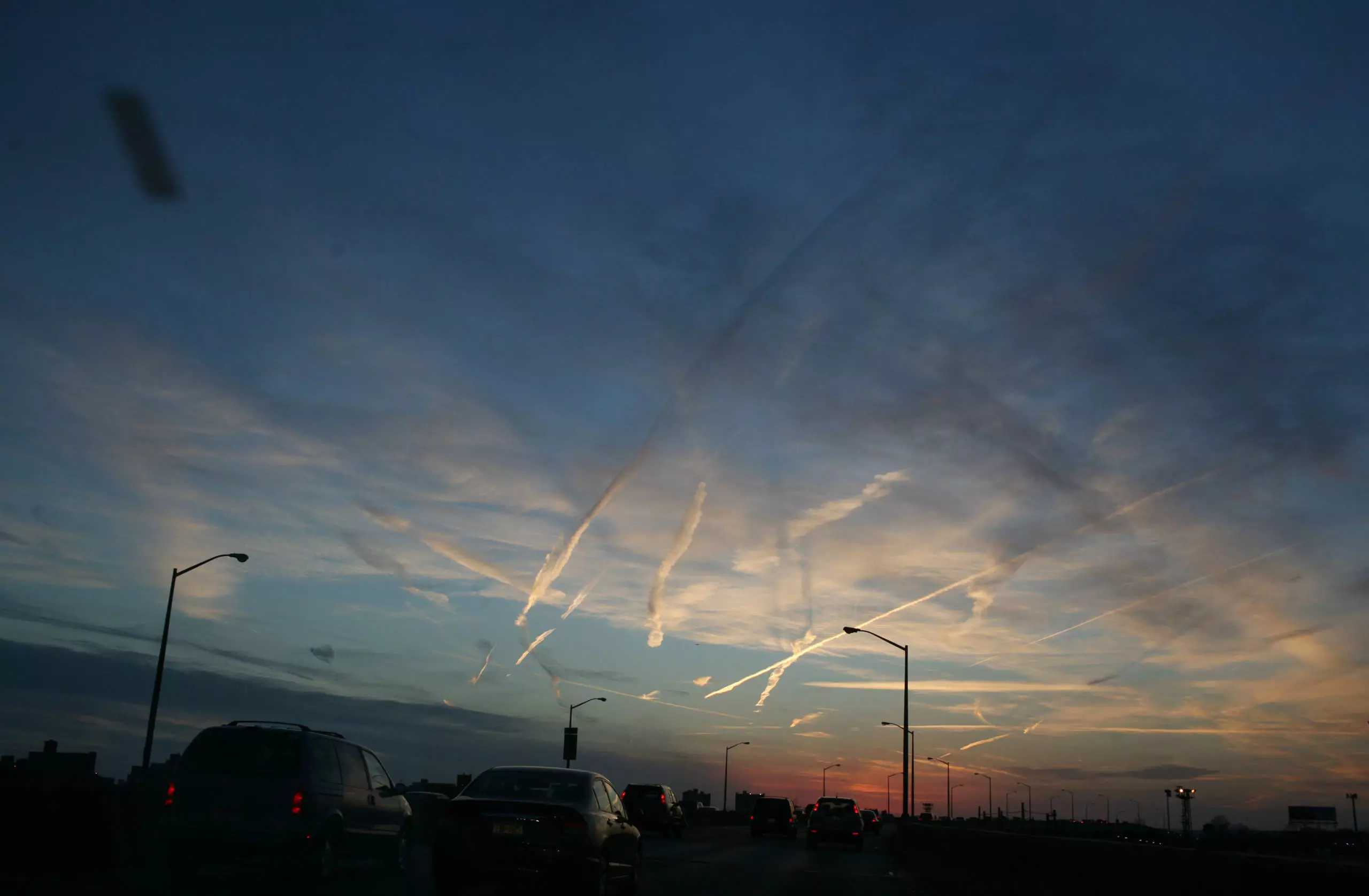 Jet contrails កើនឡើងពីលើចរាចរណ៍នៅលើ Belt Parkway ។ (រូបថតដោយ Andrew Lichtenstein/Corbis តាមរយៈរូបភាព Getty)