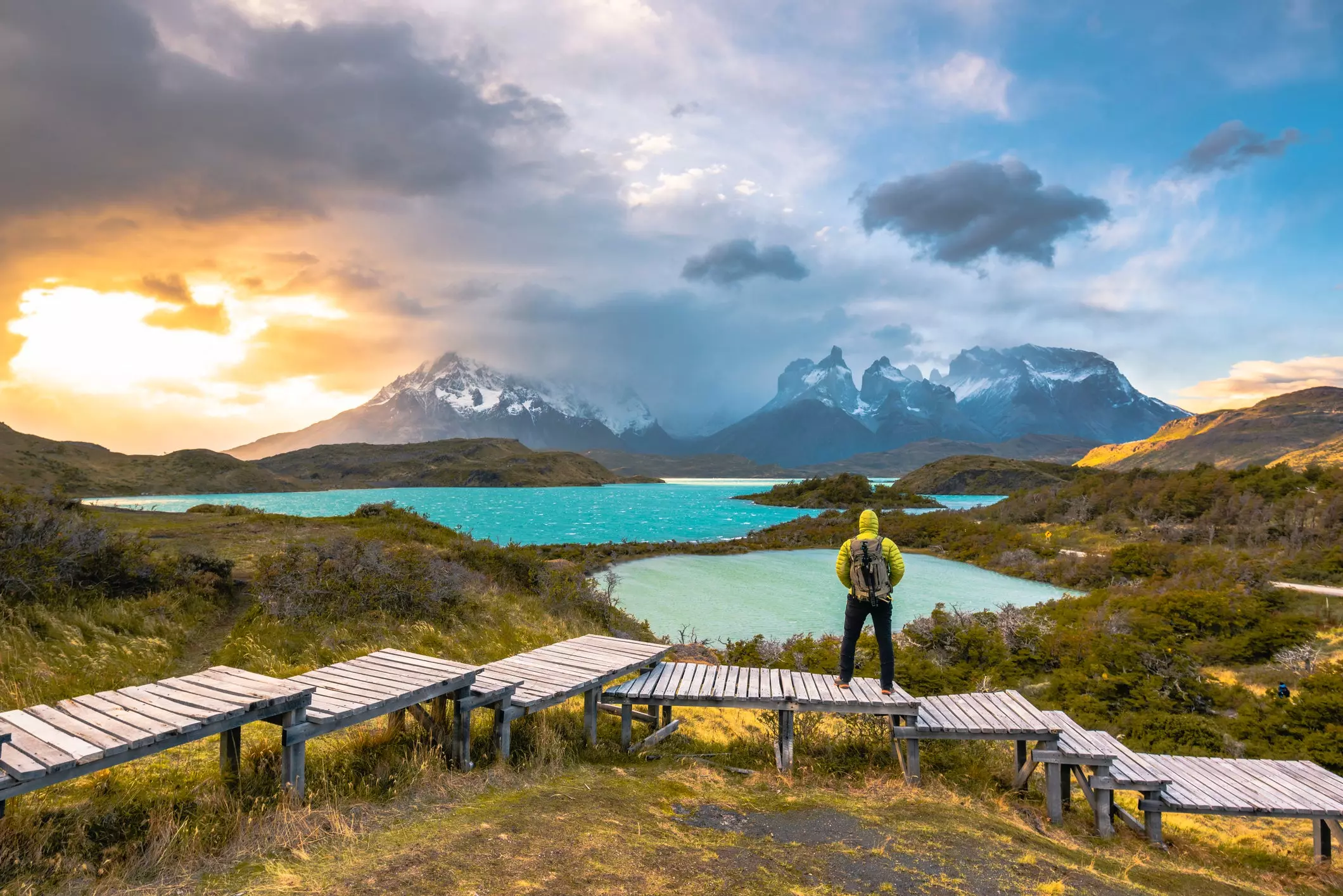 Turysta podziwiający jezioro Pehoe i pasmo Torres del Paine o zachodzie słońca, Chile