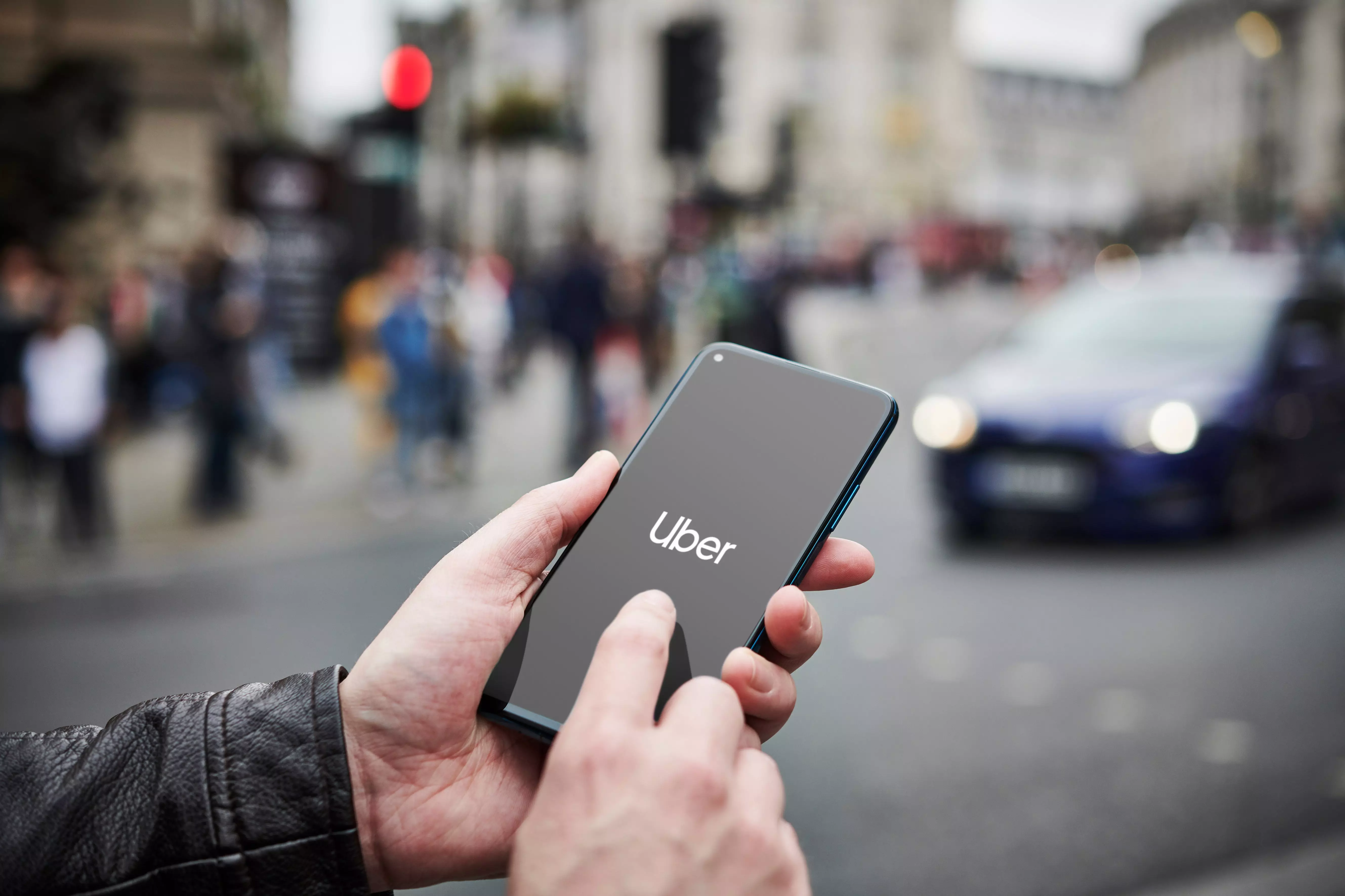 LONDRA, REGATUL UNIT - 4 IUNIE: Detaliu al unui bărbat care ține în sus un smartphone Honor 20 Pro cu aplicația de transport Uber vizibilă pe ecran, în timp ce taxiurile stau la coadă în fundal, pe 4 iunie 2019. (Foto de Olly Curtis/Future via Getty Imagini prin Getty Images)