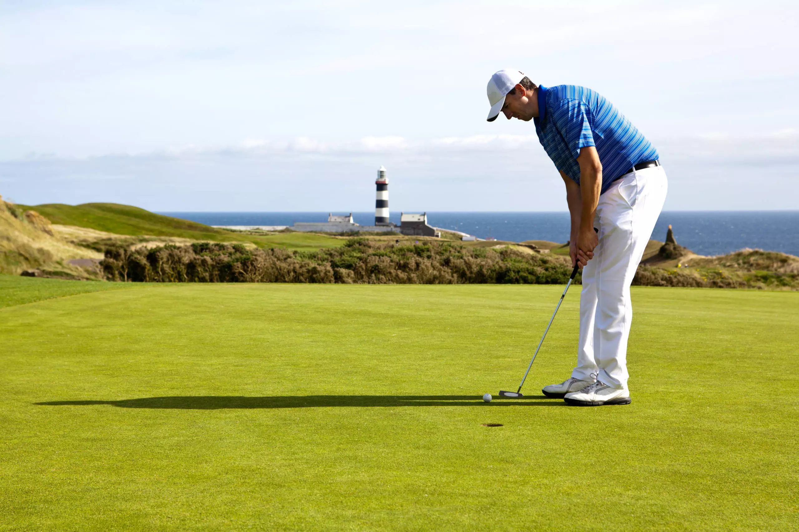 O lo'o fa'aofuina e Golfer se lanu meamata ma le sami ma le Old Head of Kinsale moli moli i tua.