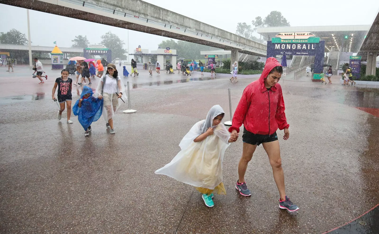 Menschen verlassen Disneys Magic Kingdom-Themenpark bei starkem Regen, nachdem er in Orlando, Florida geschlossen wurde, um sich auf die Landung des Hurrikans Matthew am 6. Oktober 2016 vorzubereiten. (Foto von GREGG NEWTON/AFP/Getty Images)