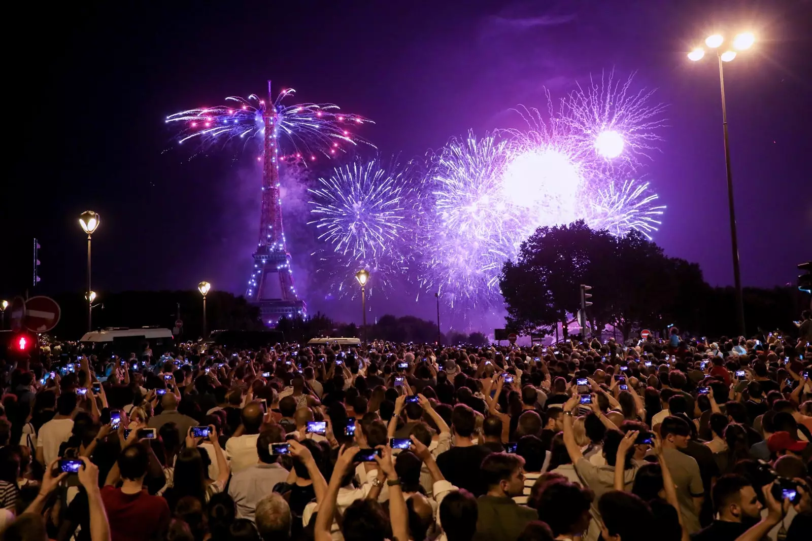 Cilvēki bauda tradicionālo Bastīlijas dienas uguņošanu virs Eifeļa torņa no Pont de l'Alma tilta 2018. gada 14. jūlijā Parīzē. (Foto Ludovičs Marins/AFP/Getty Images)