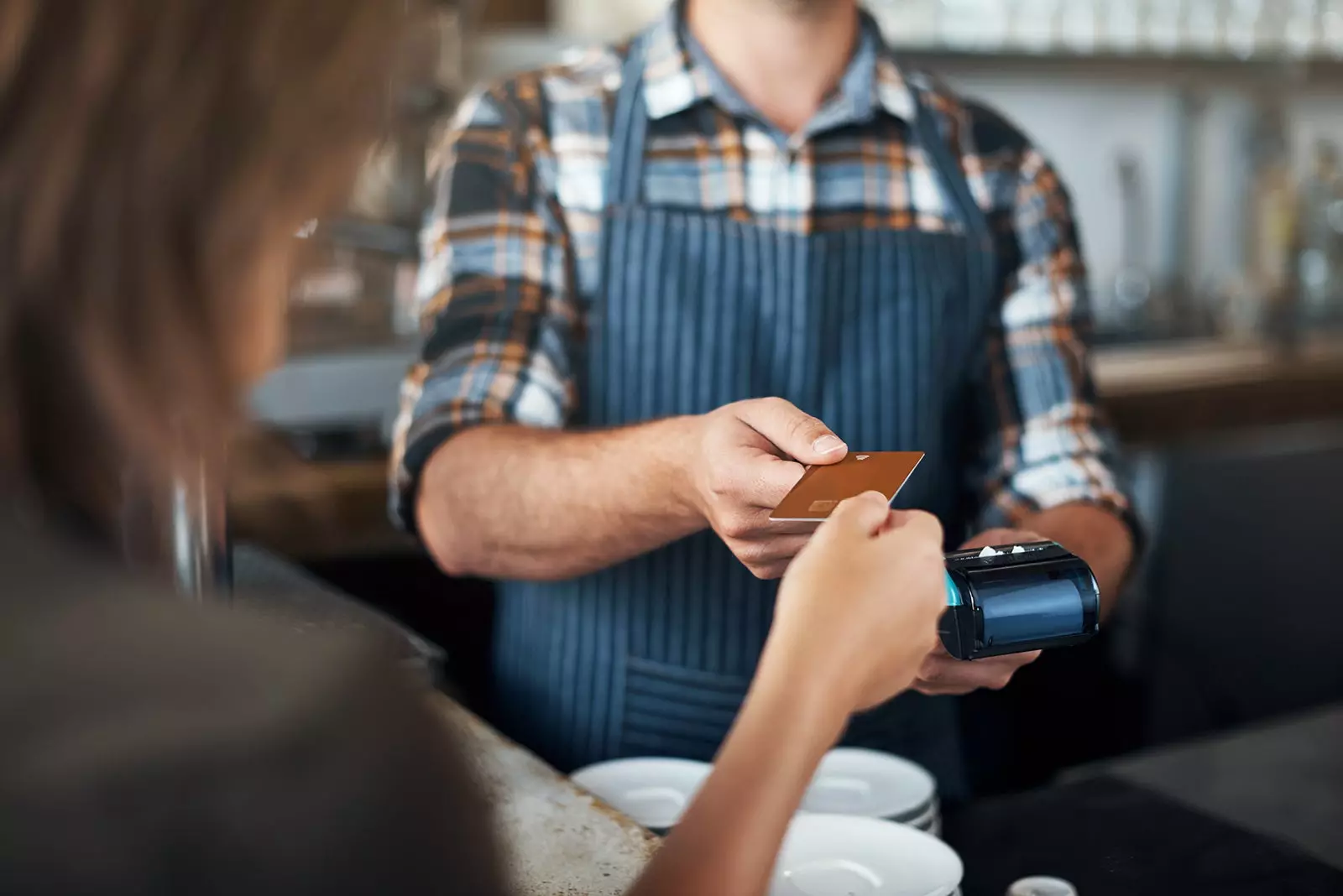 Imagine în prim-plan a unei persoane de nerecunoscut care îi dă unui barman un card de credit ca plată în interiorul unui restaurant