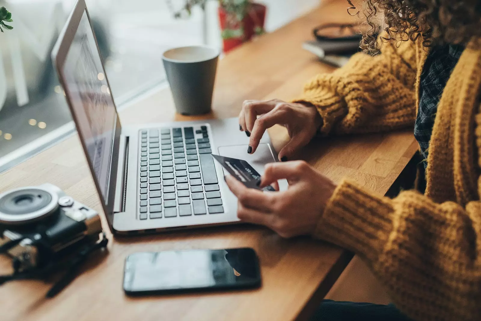 Fra am Café Shopping online mat Laptop. Foto vun filadendron / Getty Biller