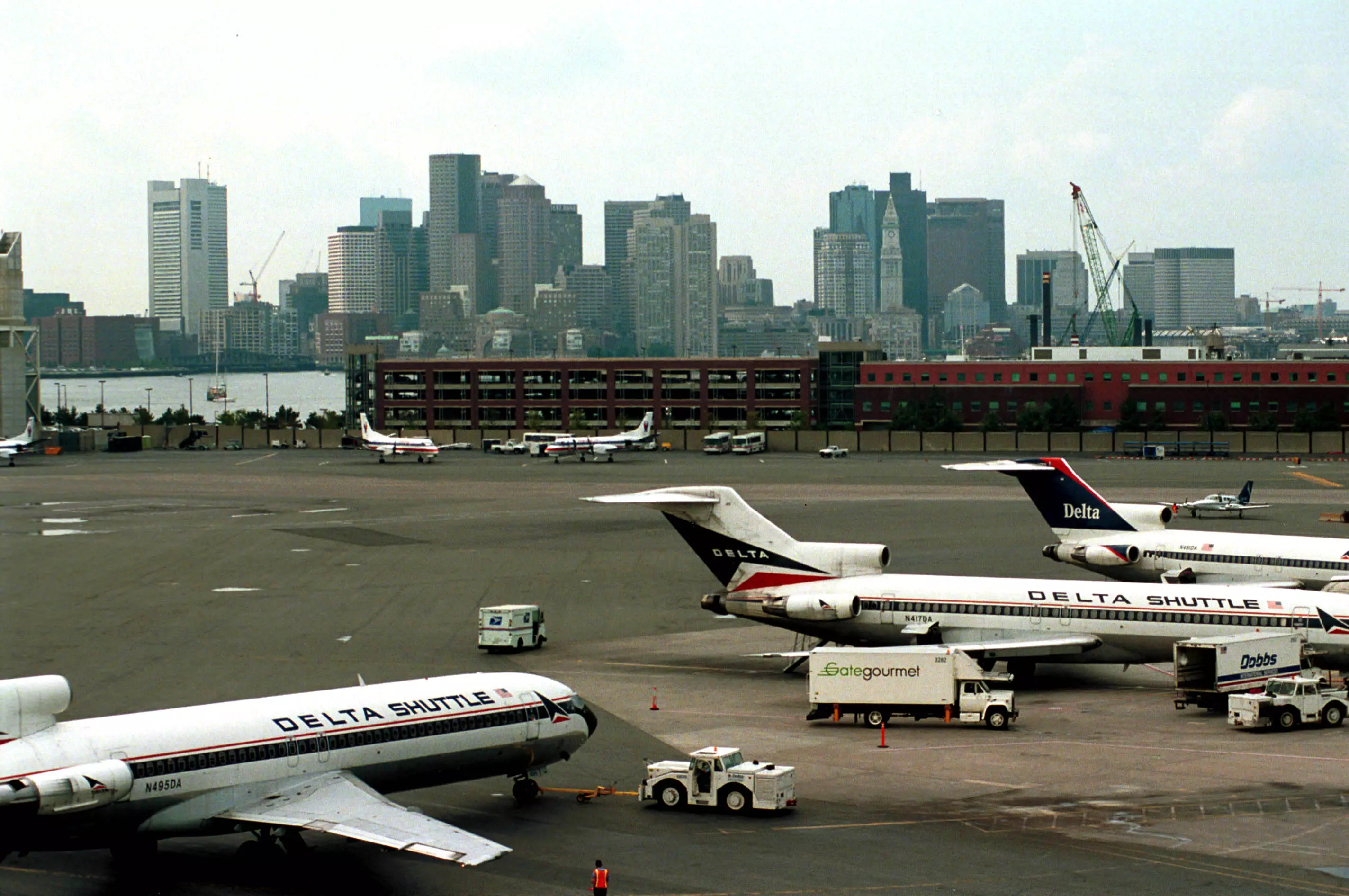 376874 03: Seasann scairdeanna Delta Shuttle ag Aerfort Logan agus cathair Boston mar chúlra 24 Lúnasa, 2000. Chuaigh oifigigh de chuid Údarás Calafoirt Massachusetts ar camchuairt le déanaí ag Pease International Trade Port i New Hampshire, ag scrúdú é mar bhealach chun brú tráchta ag Aerfort Logan a mhaolú. (Grianghraf le Darren McCollester/Nuachtoirí)