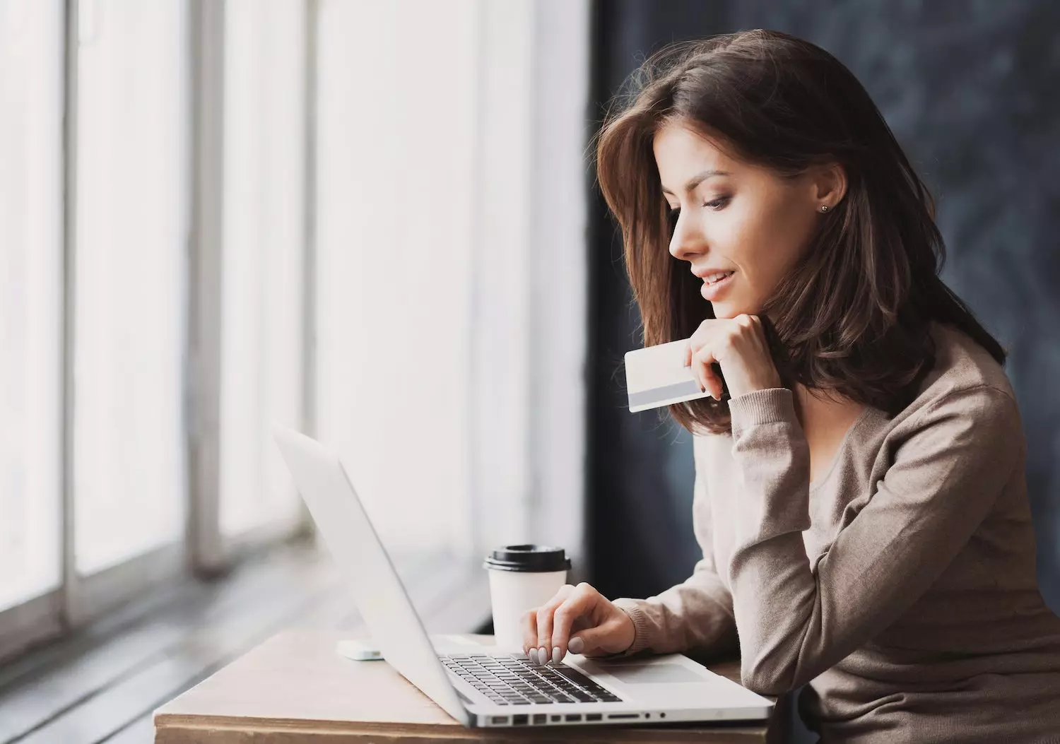 mujer, tenencia, tarjeta de crédito, delante de, computador portatil