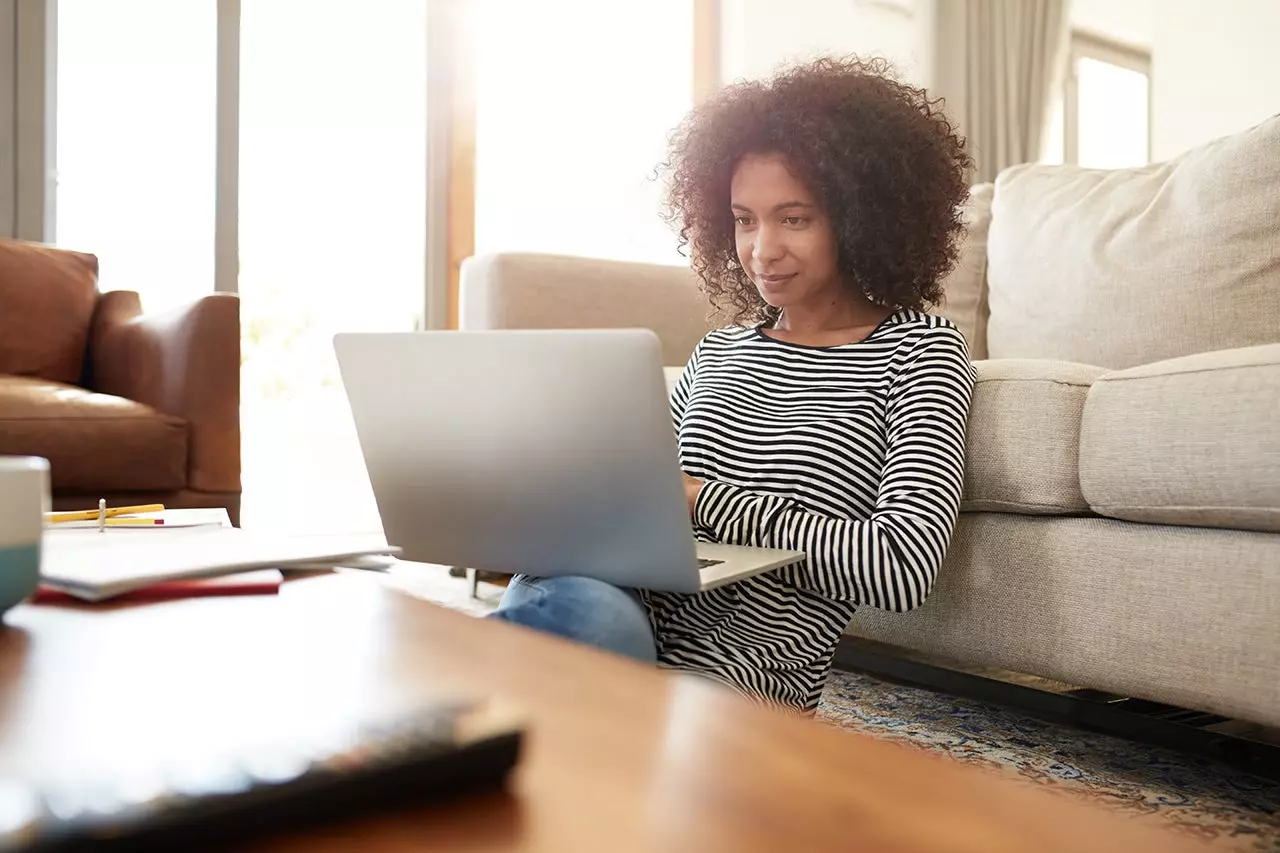 Skoot van 'n jong vrou wat met haar skootrekenaar by die huis ontspan. (Foto deur Squaredpixels/Getty Images)